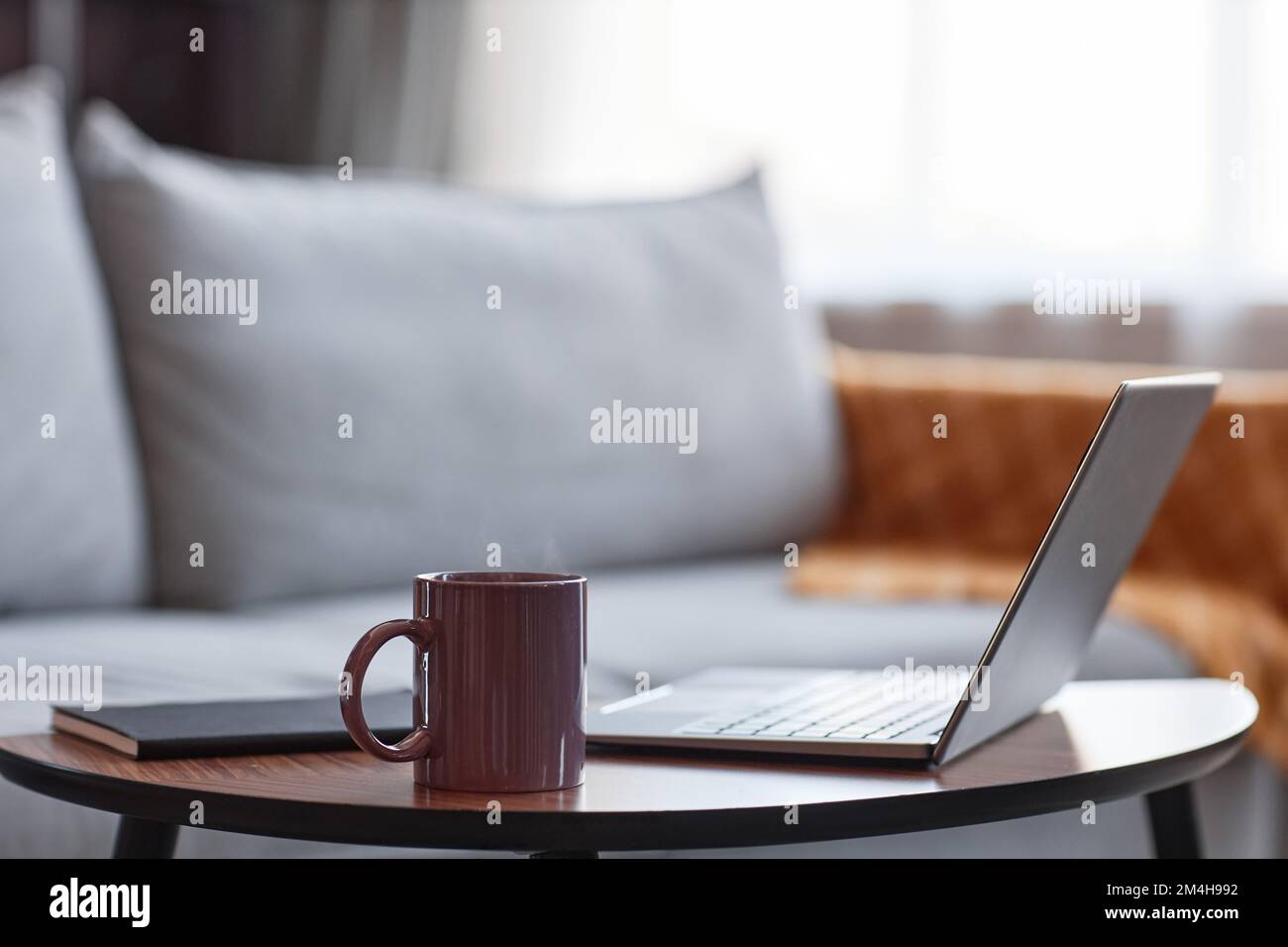 Background image of mauve coffee mug next to open laptop in cozy home ...