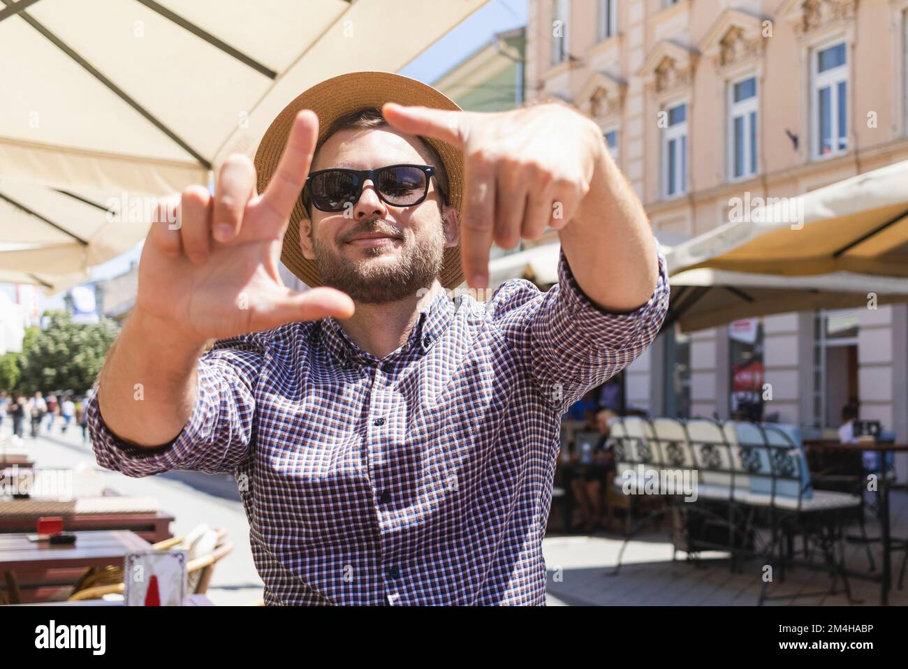 Man in sunglasses and sun hat framing with hands, finger frame Stock ...
