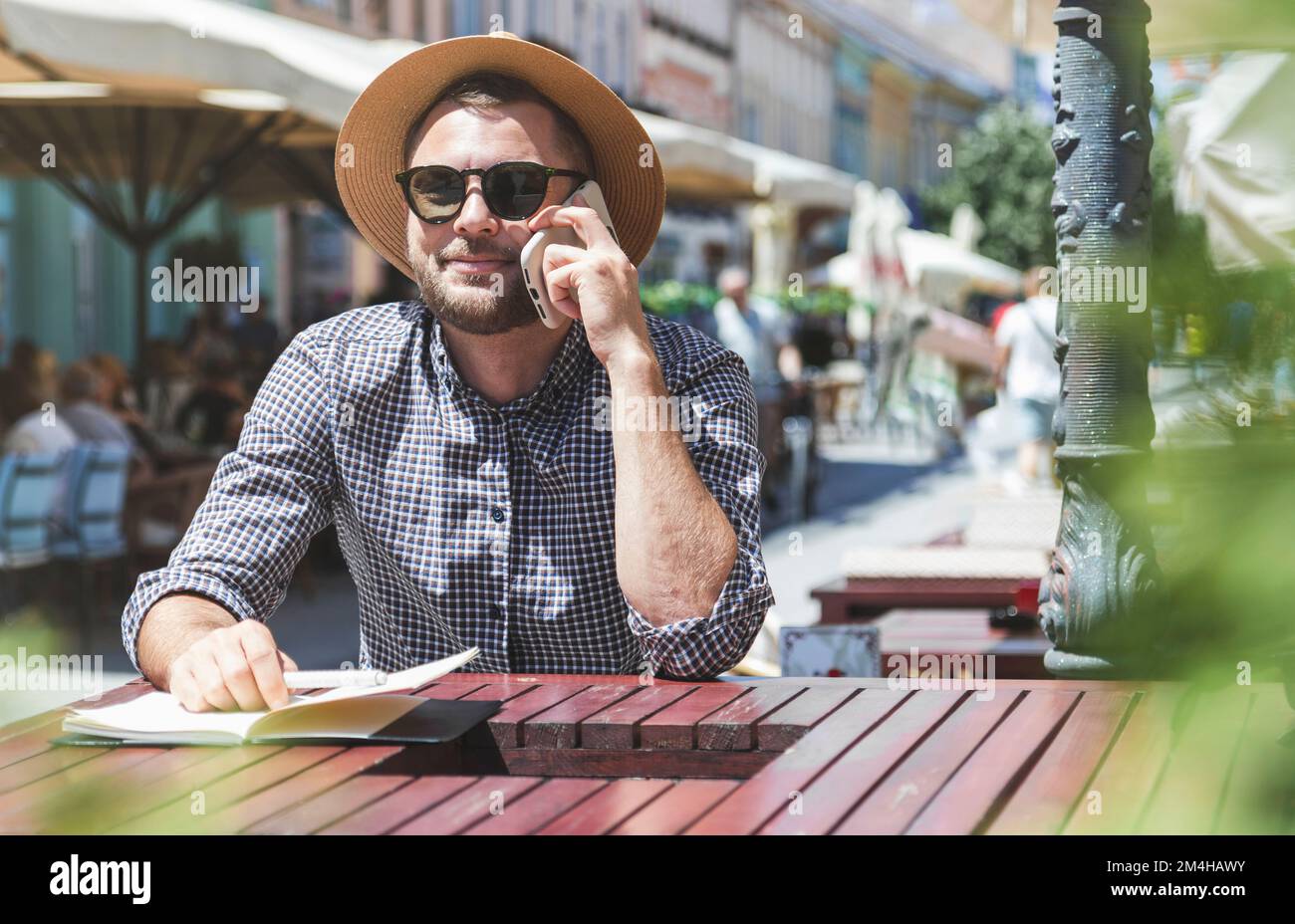 Man calling on mobile phone sitting in outdoor cafe Stock Photo - Alamy