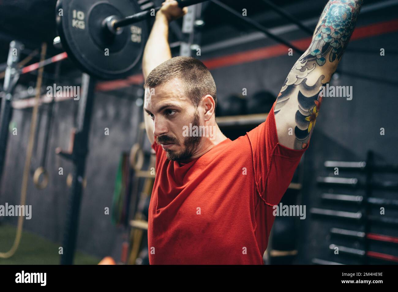 Profile of a strong and concentrated man lifting weight in a gym Stock ...
