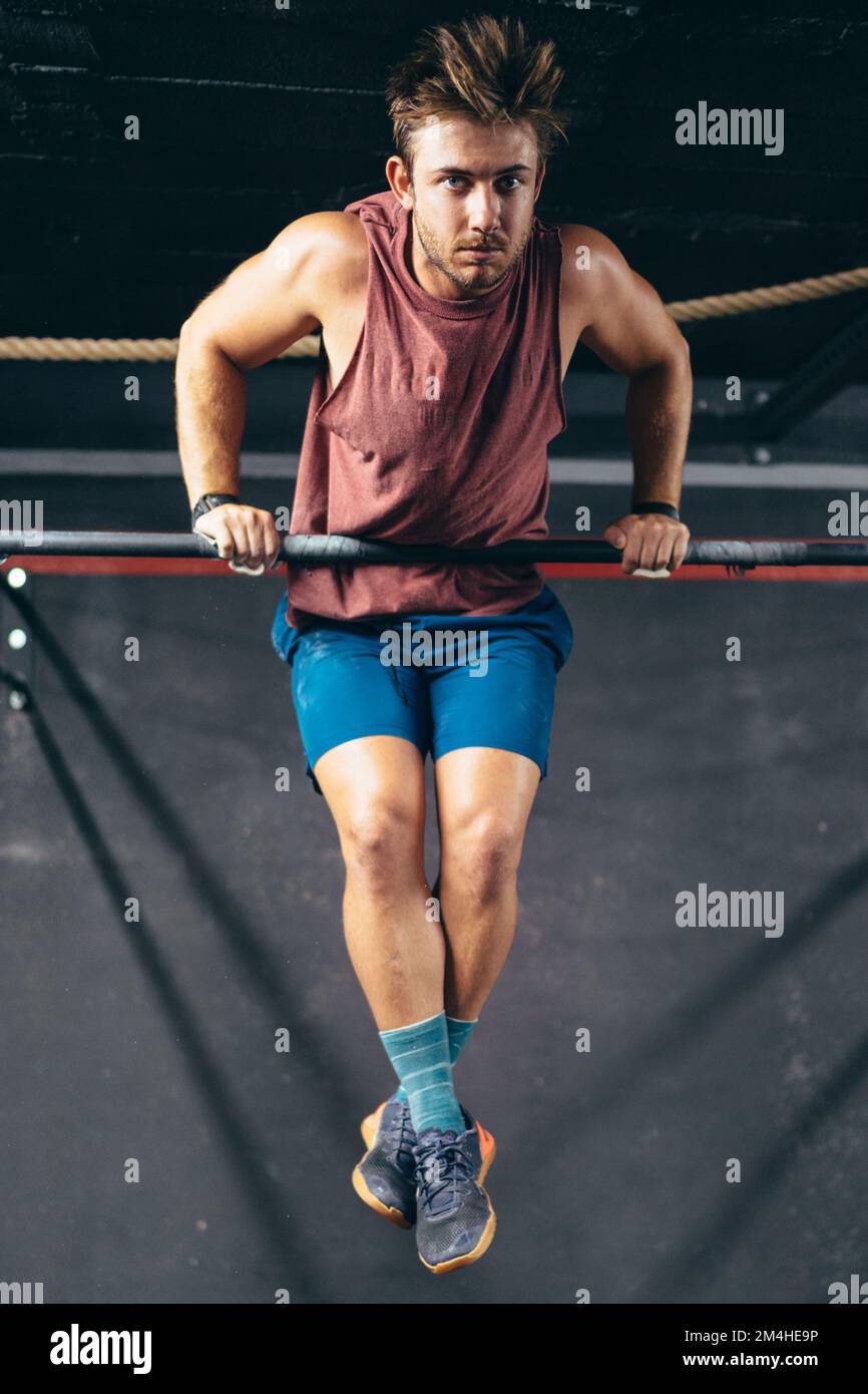 Vertical portrait of a strong man exercising in a gym using a bar Stock ...