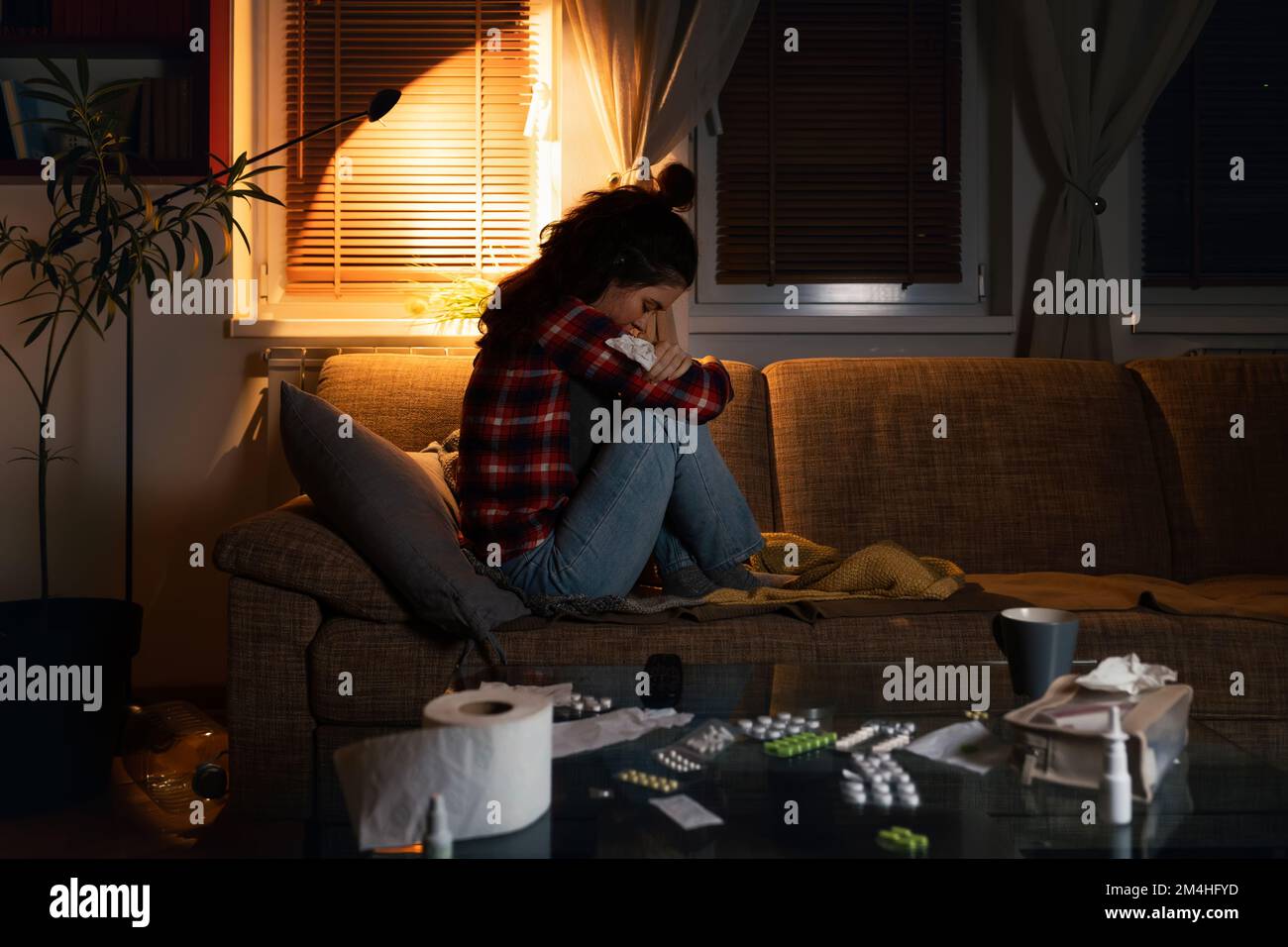 Side view of caucasian woman suffering from grief is sits hunched up on ...