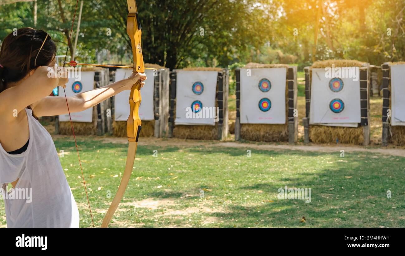 Hands of woman aims archery bow and arrow to colorful target in ...