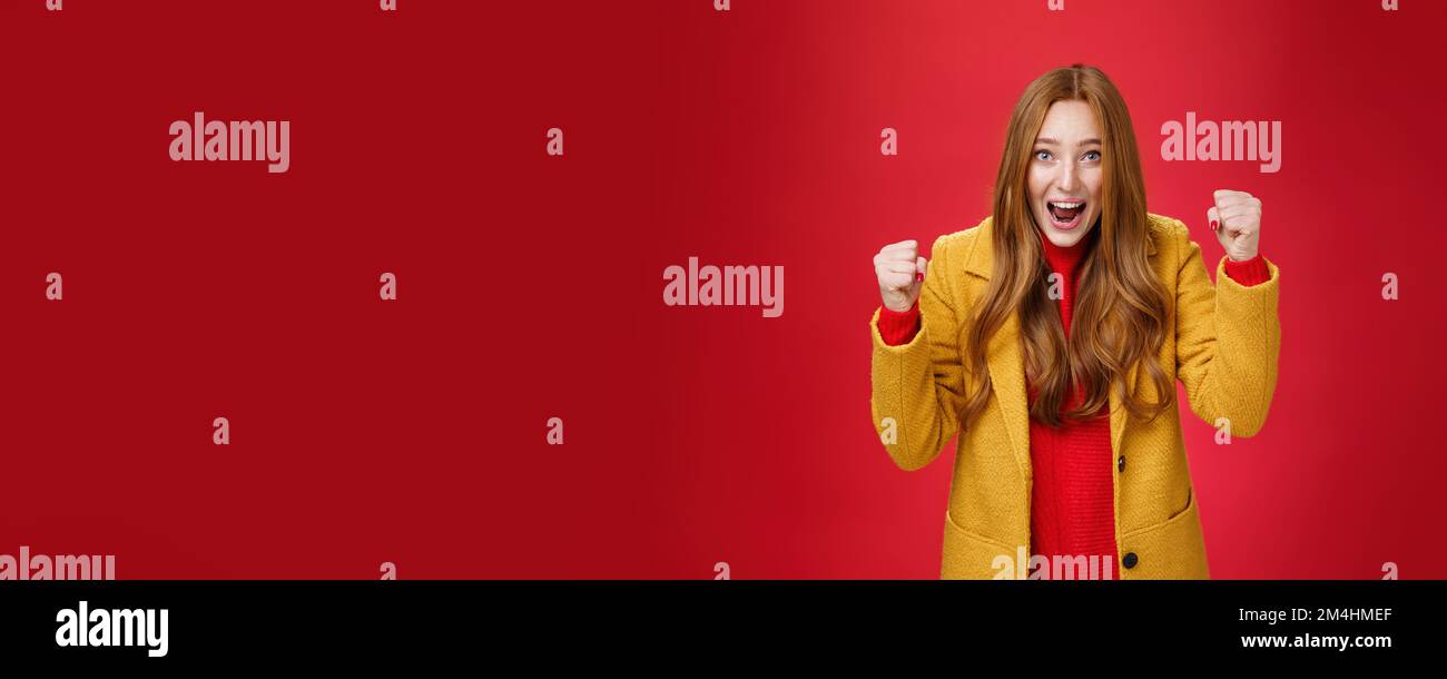 Studio shto of cheerful excited good-looking ginger girl in yellow coat ...