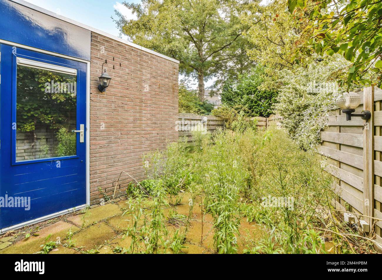 an outside view of a house with blue doors and bushes in the fore ...