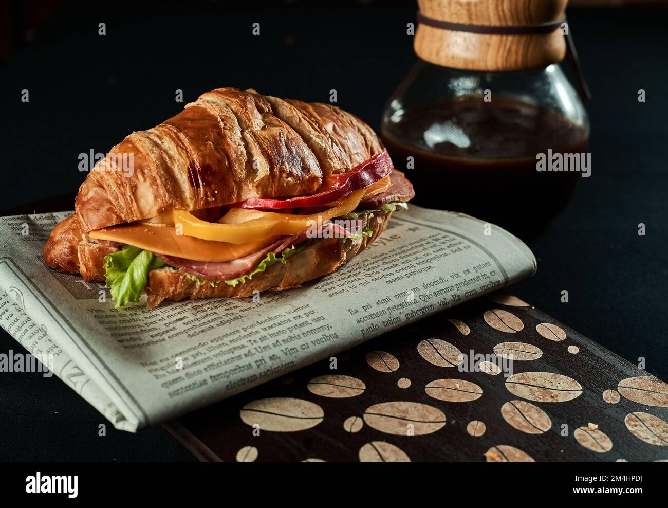 A closeup shot of a croissant sandwich on a newspaper Stock Photo - Alamy