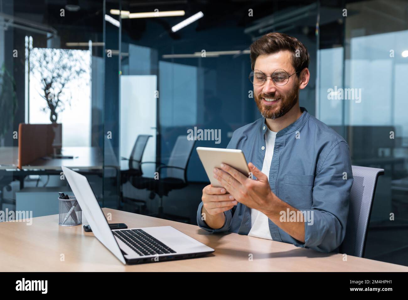 Successful businessman in a shirt uses a tablet computer, a man sits at ...