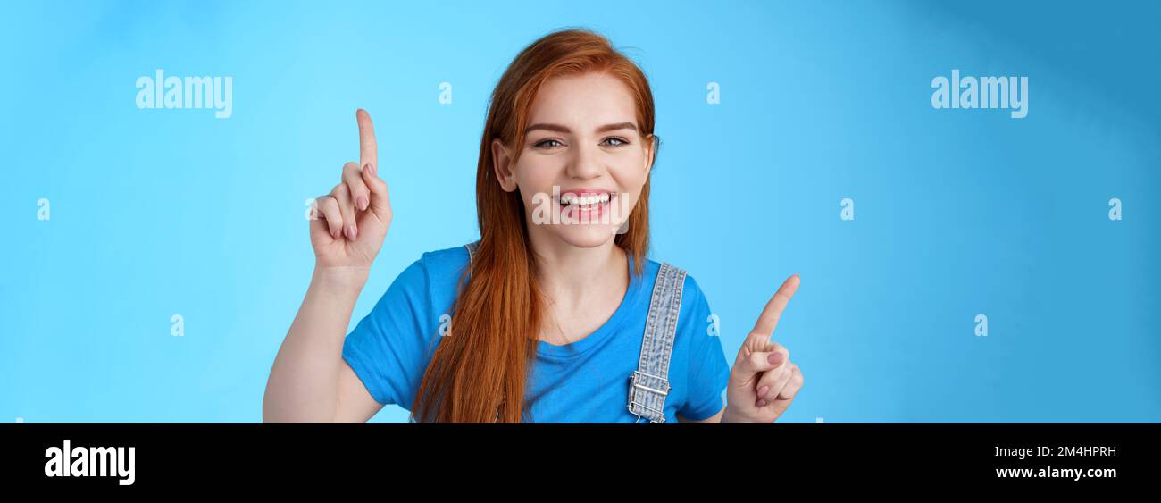 Close-up cheerful carefree redhead dancing girl pointing up, raising ...