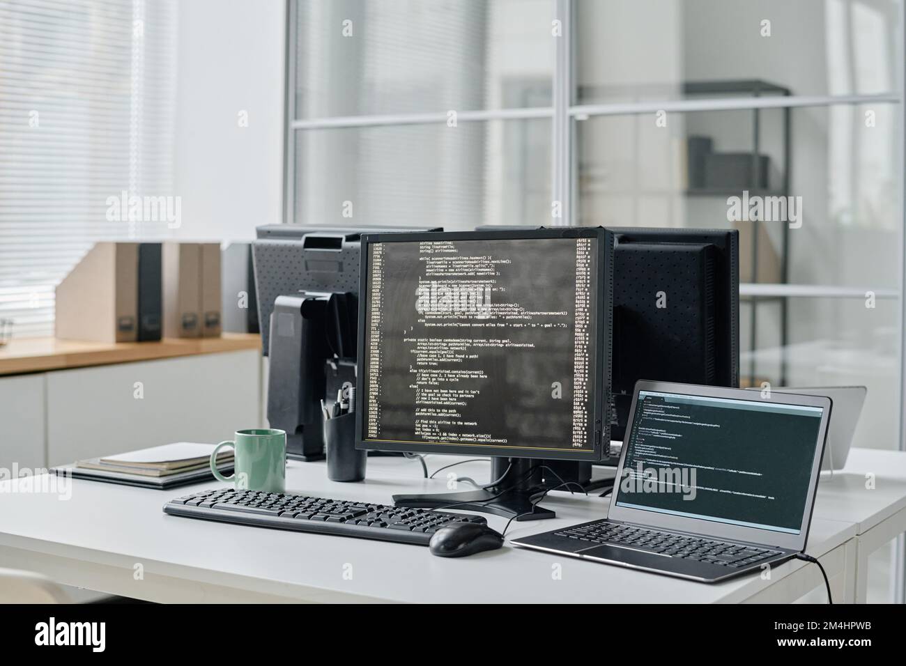 Horizontal image of workplace of programmer with computer monitors with codes on screens ...
