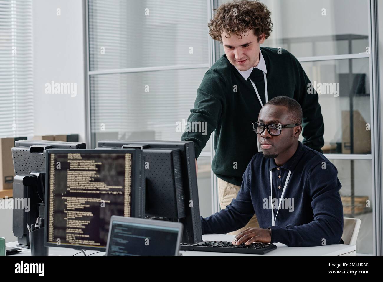 Two young colleagues discussing new program codes on computer during ...