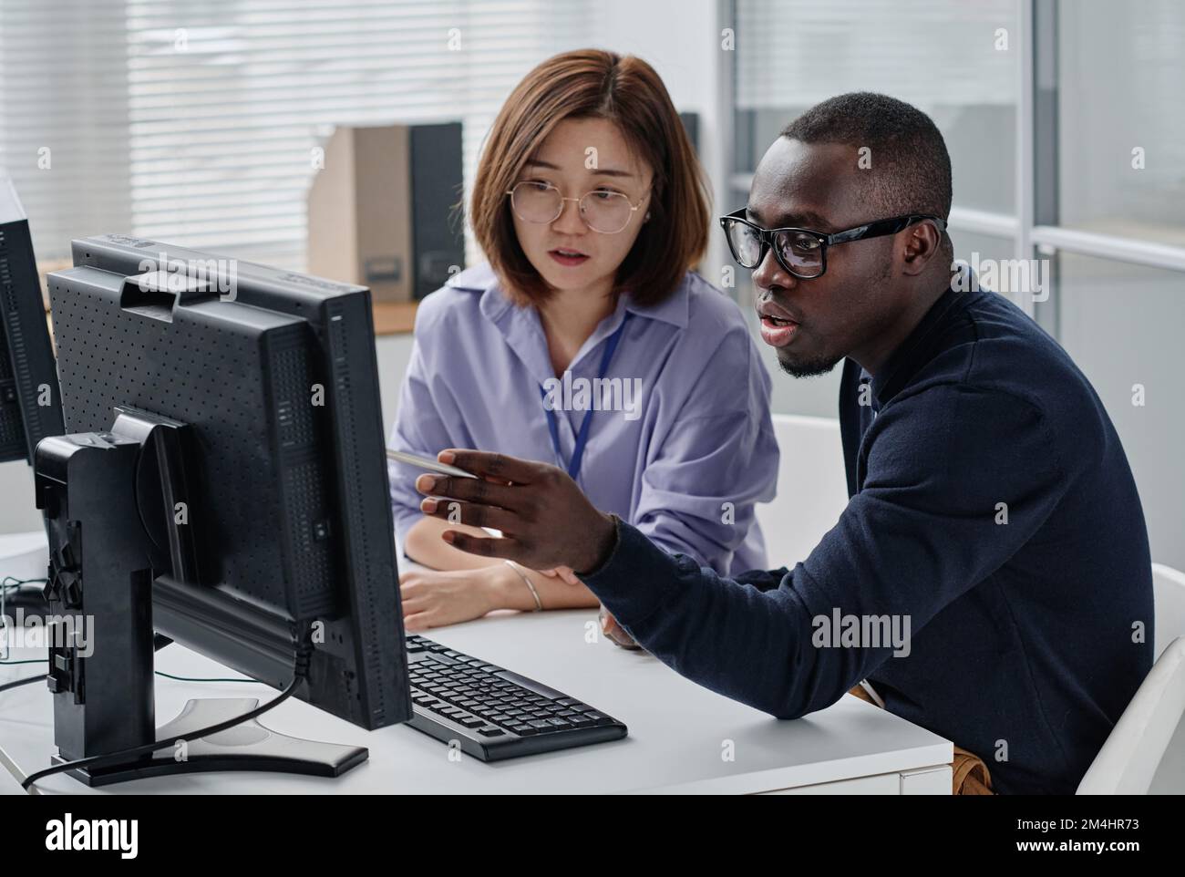 African American programmer pointing at monitor and discussing ...