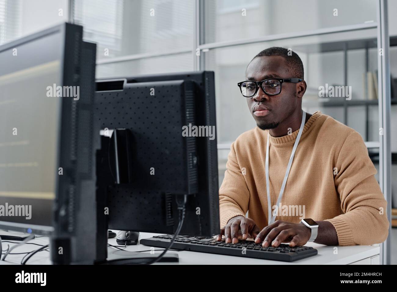 African American Programmer In Eyeglasses Concentrating On His Online Work On Computer He