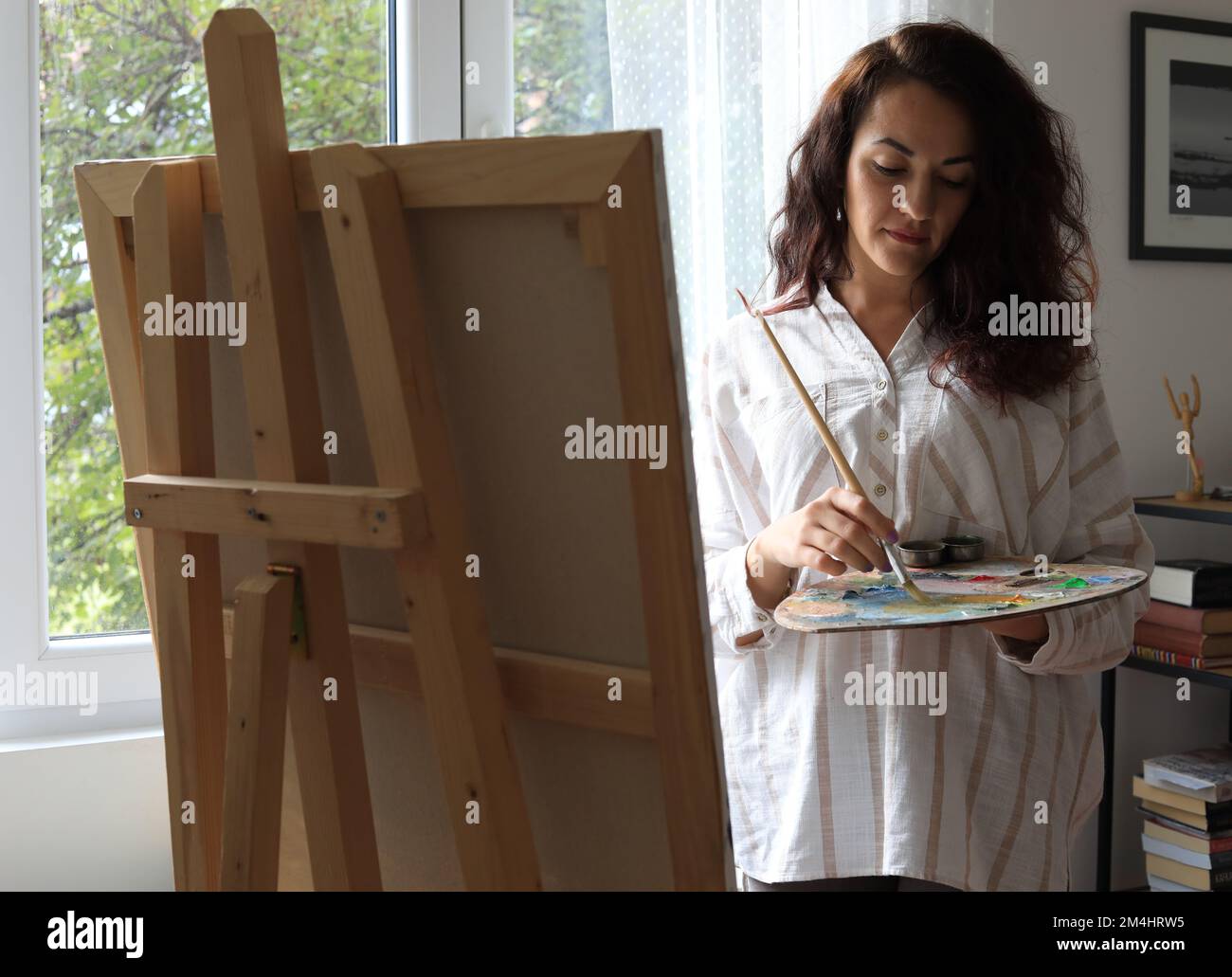 A Caucasian female painting something on an easel Stock Photo - Alamy