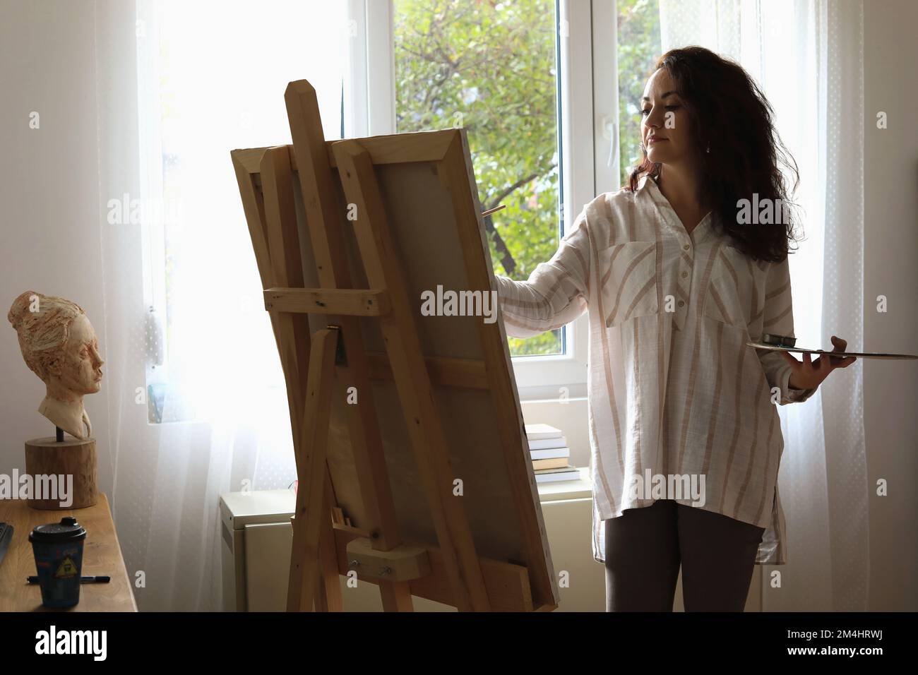 A Caucasian female painting something on an easel Stock Photo - Alamy