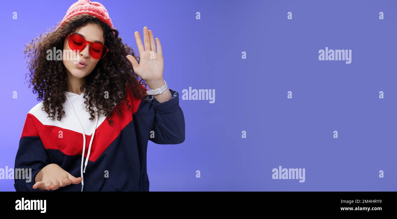 Studio shot of cool and stylish dj girl in red beanie and sunglasses ...