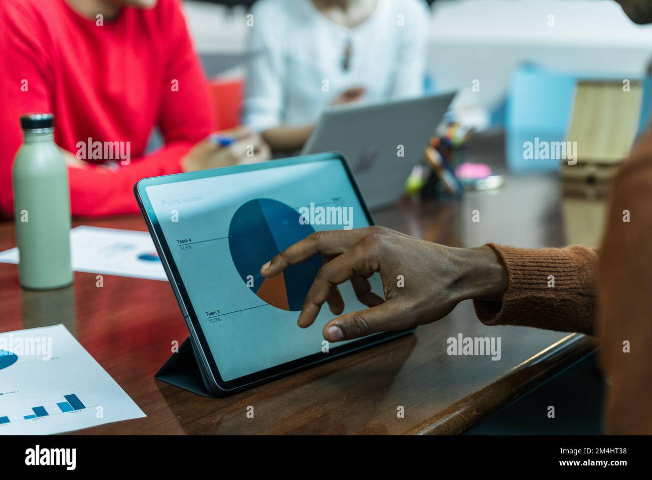 Hand of a dark-skinned man touching a digital tablet showing a pie ...
