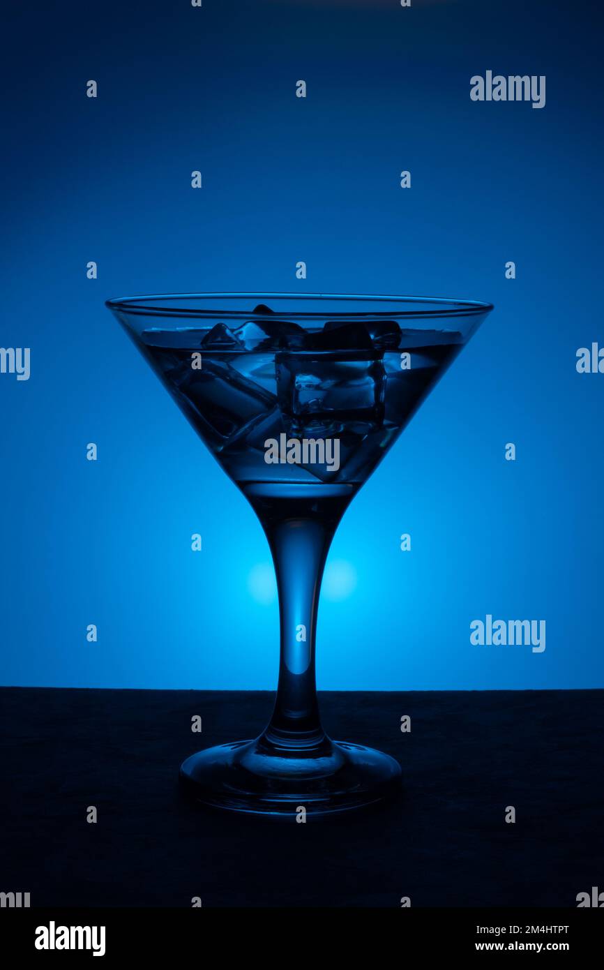 Alcoholic or non-alcoholic cocktail with ice cubes, on a blue gradient ...