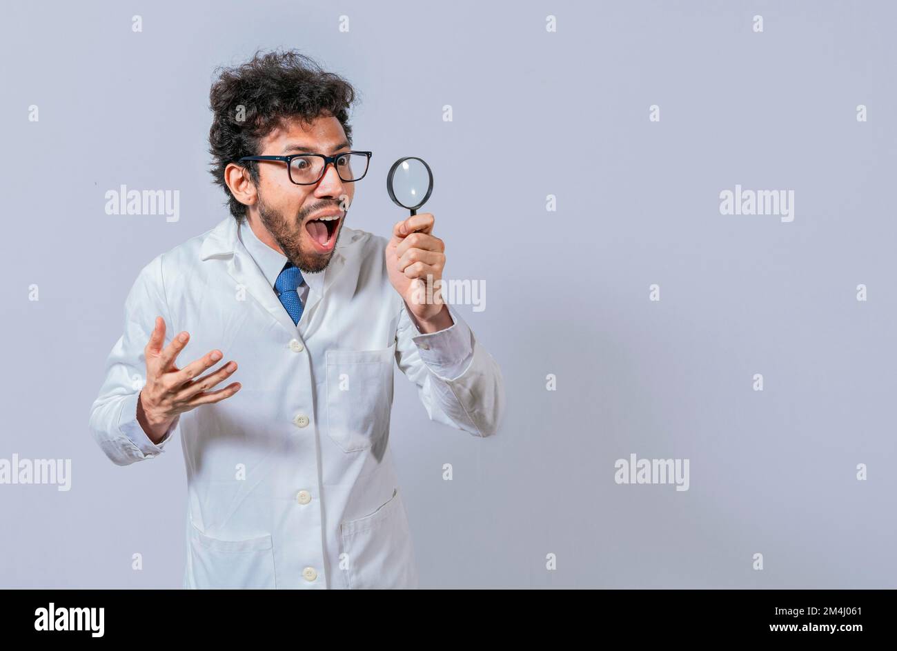Surprised scientist observing with a magnifying glass to the side ...