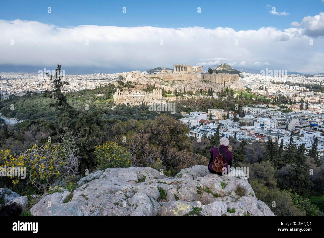 Tourist sitting on rock, view from Philopappos Hill over the city ...
