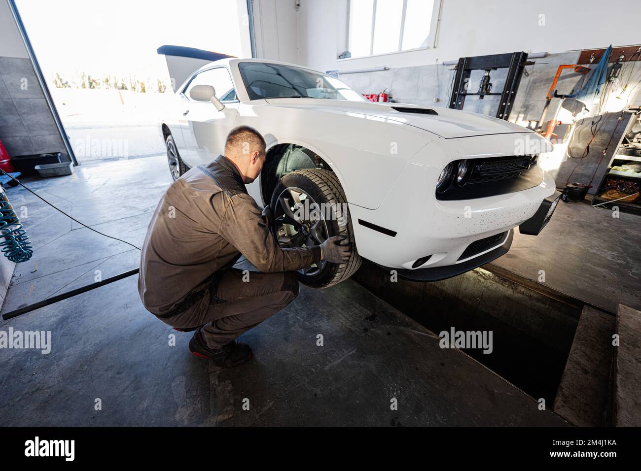 Mechanic in service repair station working with muscle car. Inspects ...
