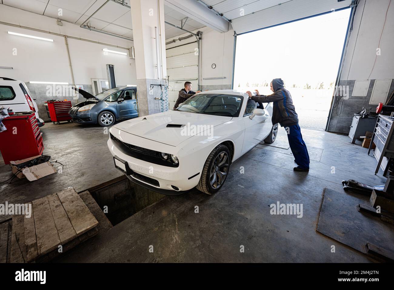 Two service man mechanics in repair station working with muscle car ...