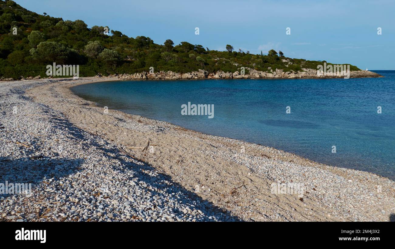 Marmakas Bay, pebble beach, wooded slope, blue almost cloudless sky ...