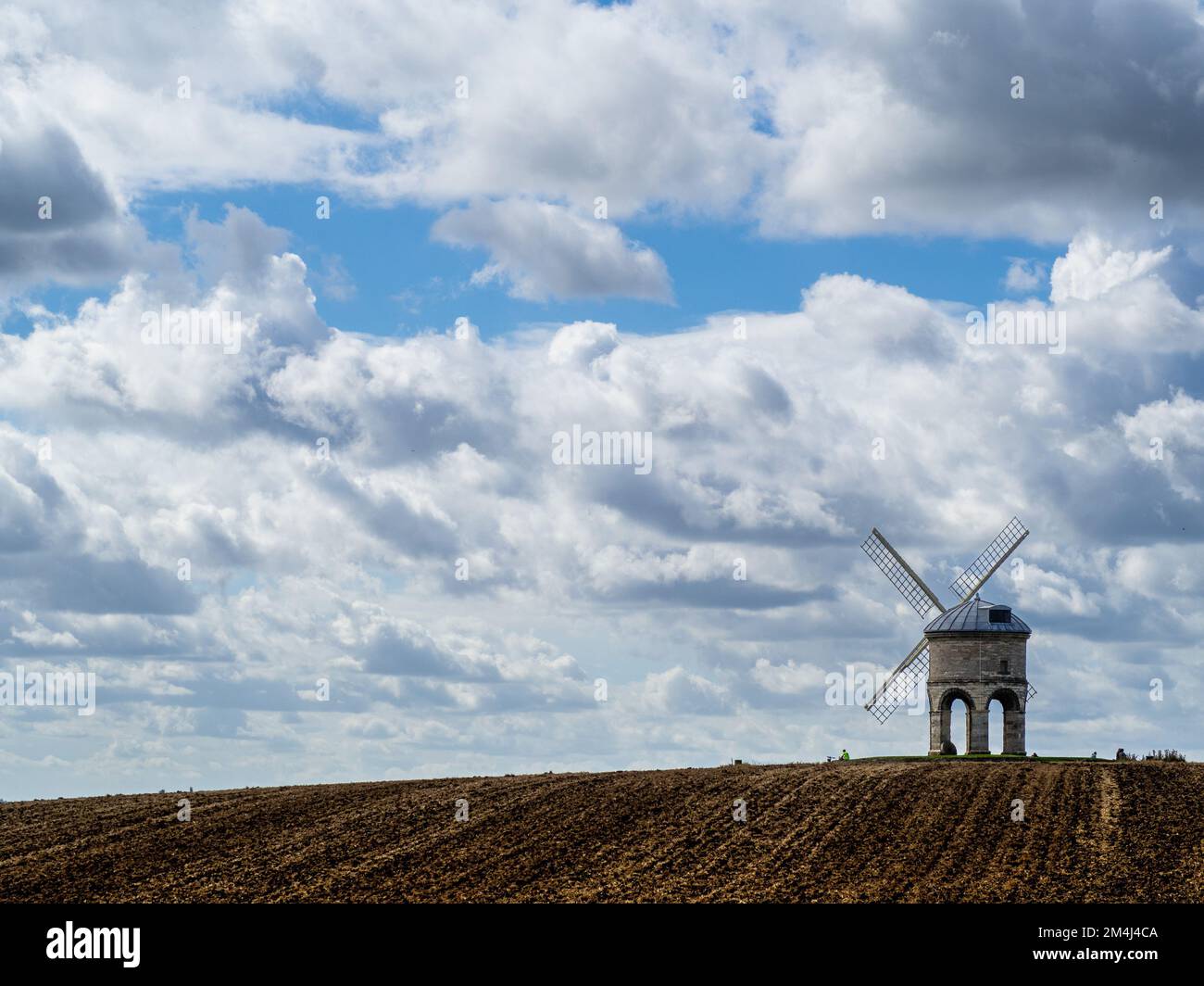 A beautiful shot of a windmill on a rural field during a golden hour ...