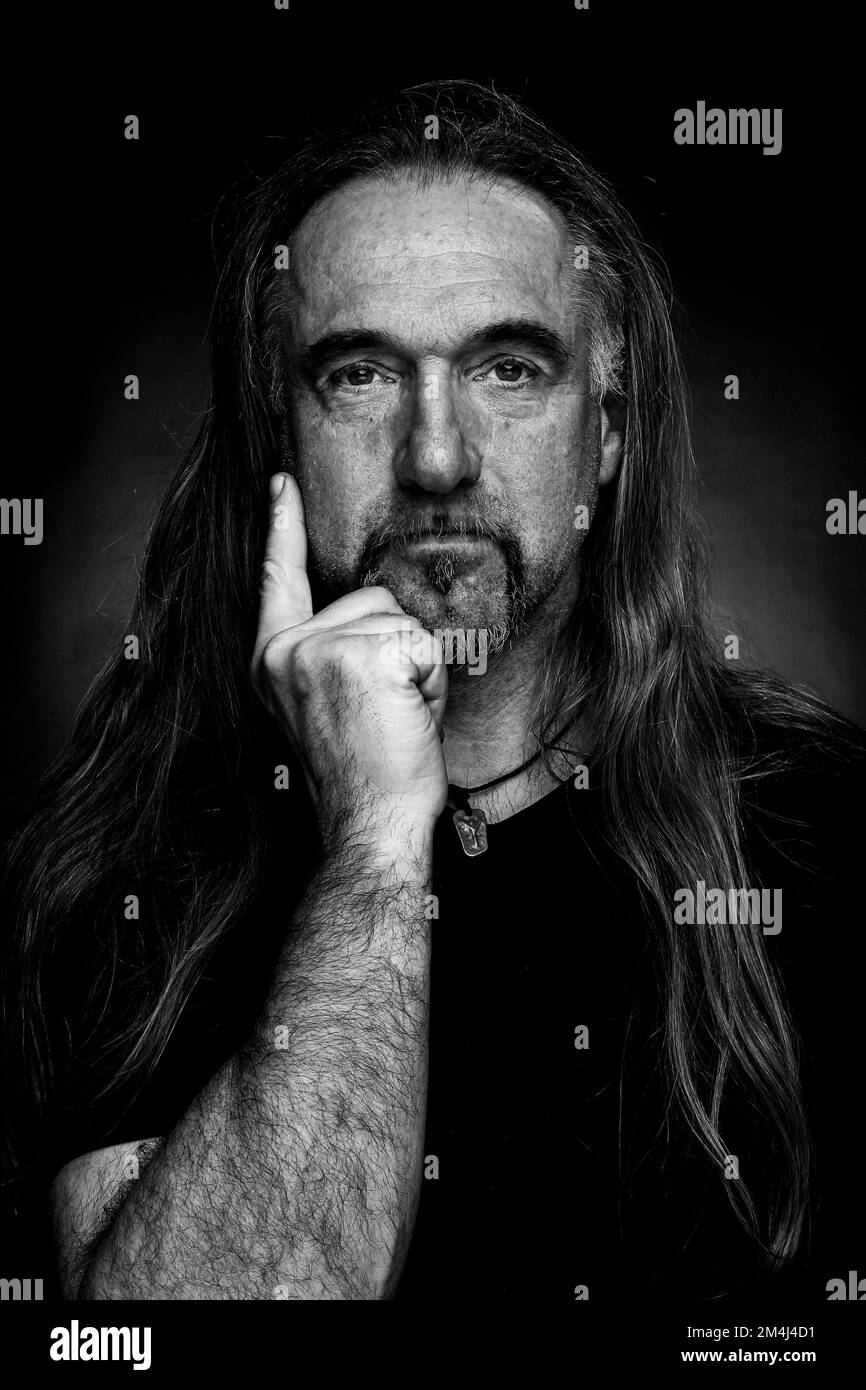 Man with long hair and hand with outstretched index finger on chin ...