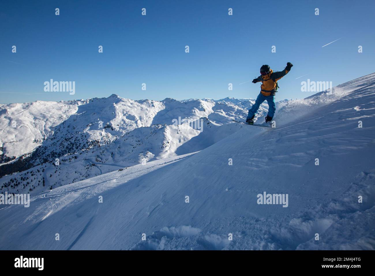 Boarder on a snowboard jumping on a beautiful day in the big mountains ...