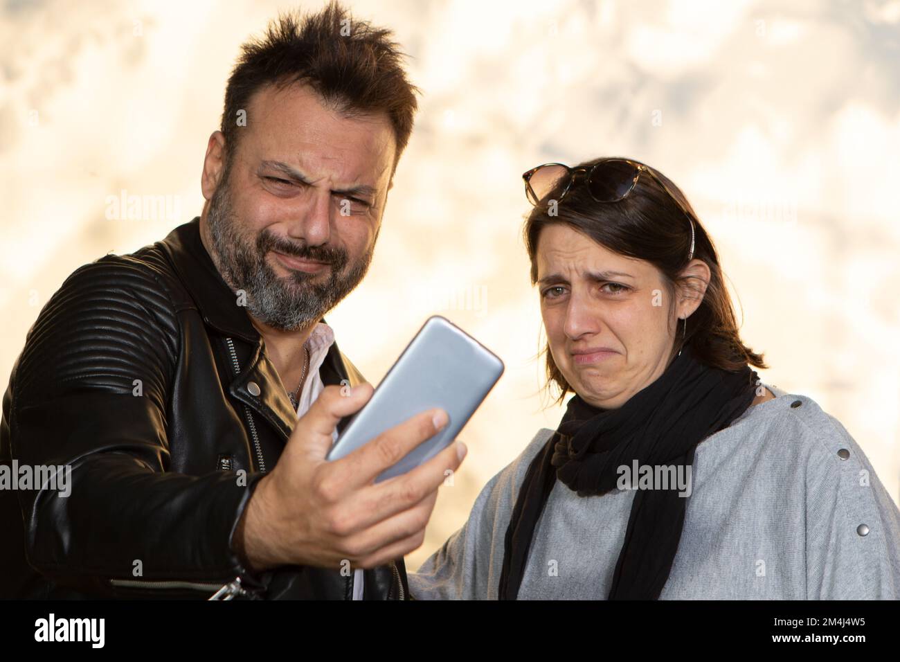 two guys watching a post on smartphone and making a cringe expression ...