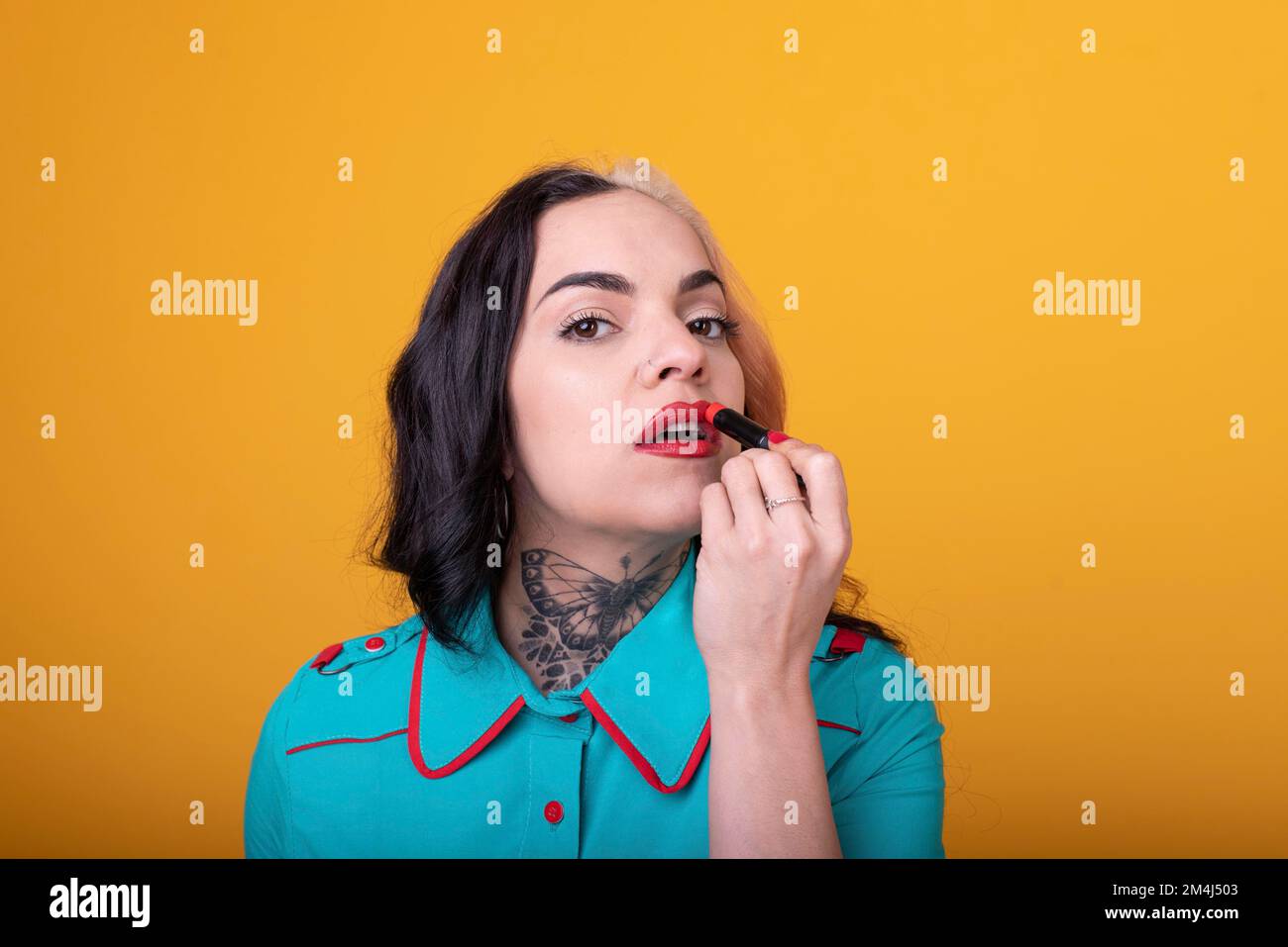 Beautiful caucasian woman applying a bright red color lipstick on her ...