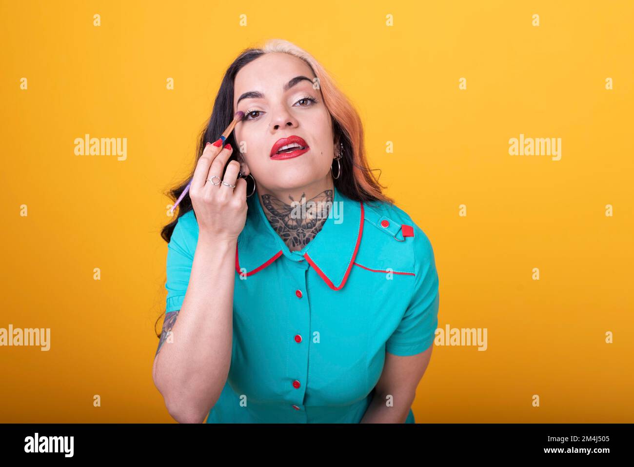 Attractive Woman Applying eye shadow over yellow Studio Background ...