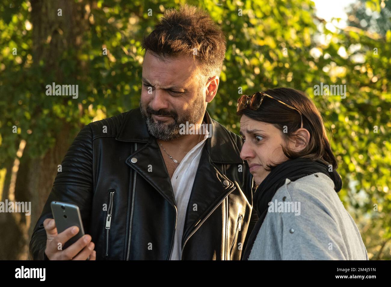 two guys watching a post on smartphone and making a cringe expression ...