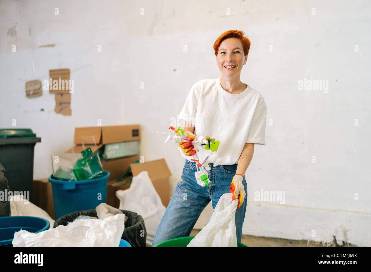 Portrait of smiling female worker wearing latex gloves sorting diverse ...