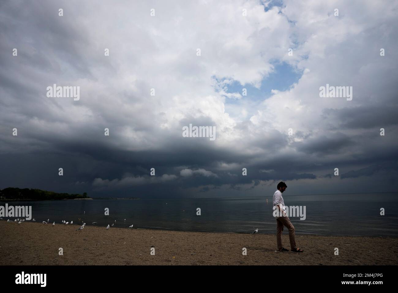 A person looks out over Lake Ontario as a thunderstorm rolls through ...