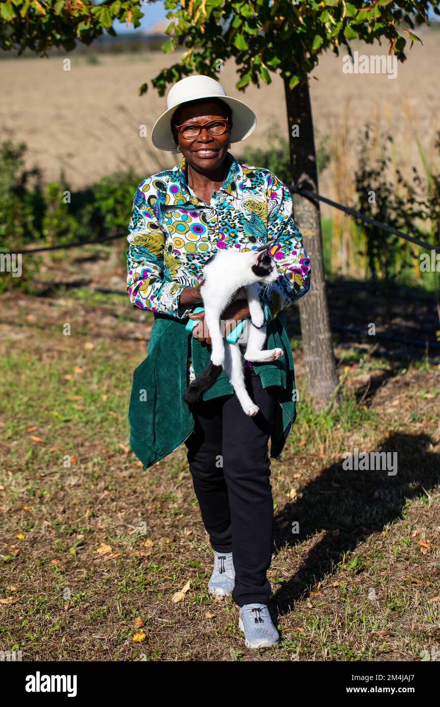 Smiling African woman with a pet cat. Portrait in exterior with the sky ...