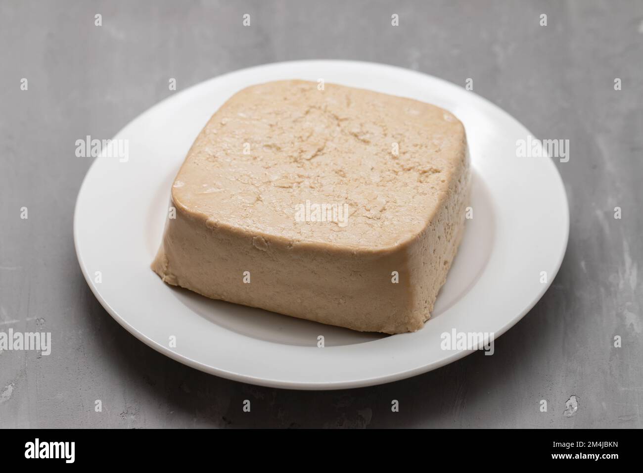 raw tofu block on white small dish on gray ceramic Stock Photo - Alamy