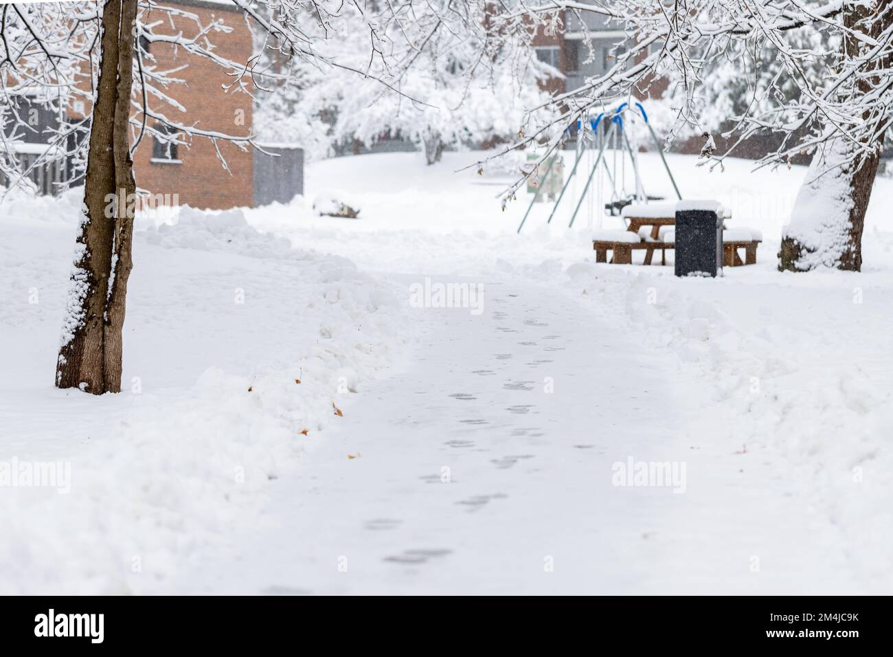 Snow on the sidewalk leading to the house and playground in the yard ...