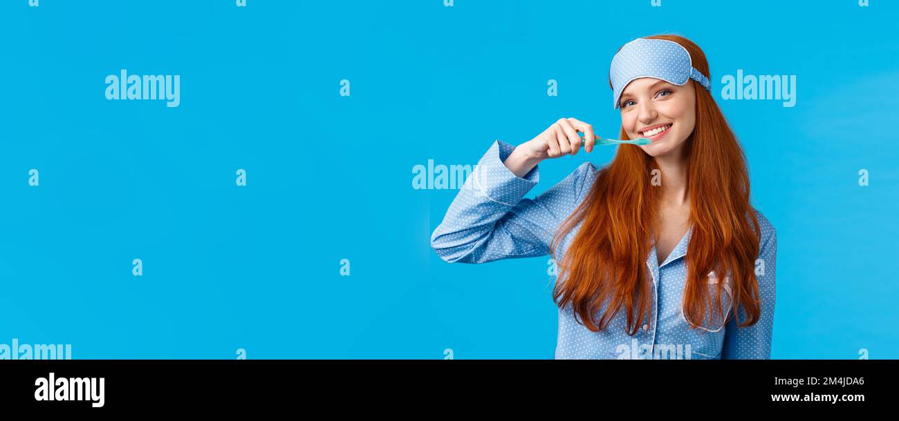 Cheerful cute redhead woman in nightwear, pyjama and sleep mask ...