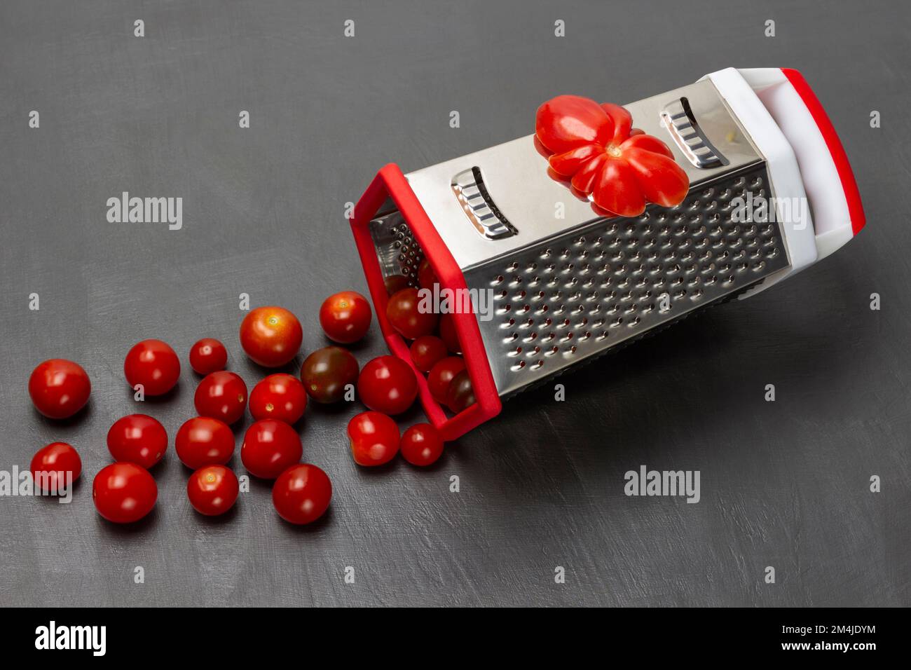 Red cherry tomatoes and red grater. Copy space. Top view. Grey ...
