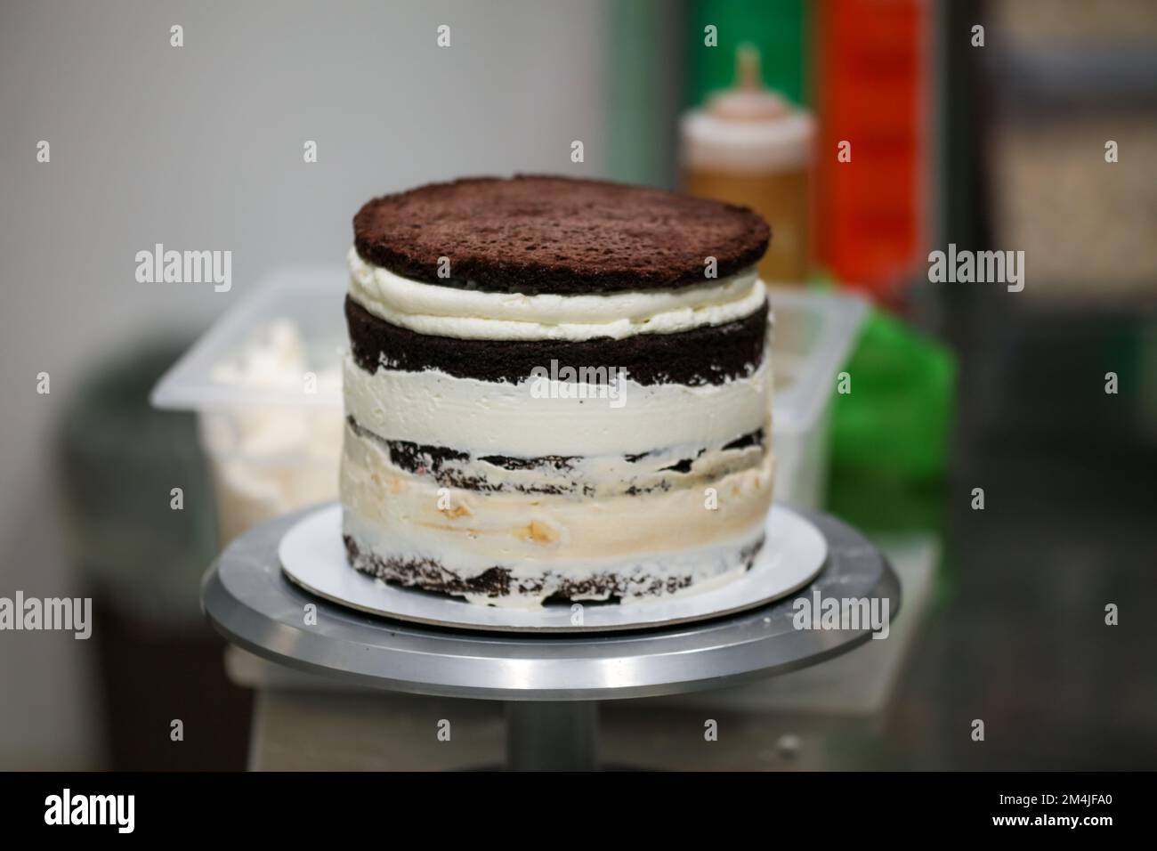 pastry chef using spatula scraper to smooth o buttercream layered tall ...