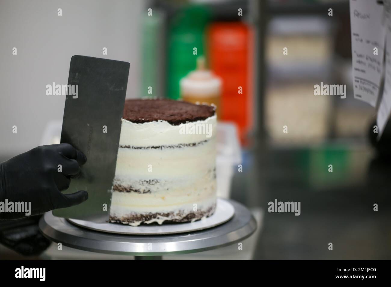 pastry chef using spatula scraper to smooth o buttercream layered tall ...