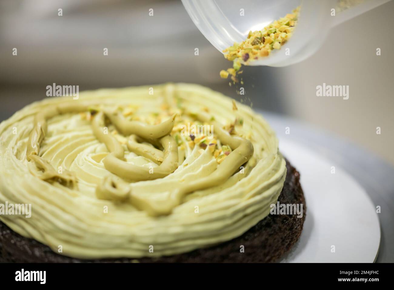 pastry chef designer using pistachio cream and sprinkles on layered ...