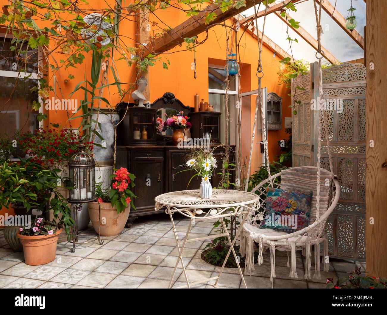 Interior of veranda. Wooden furniture. Hanging wicker chair, plants ...