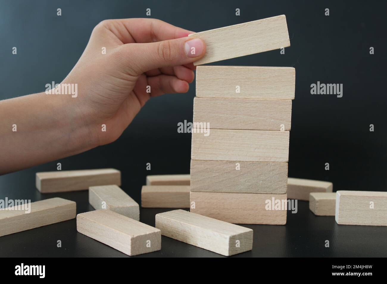 man's hand sorting wooden blocks on black background Stock Photo - Alamy