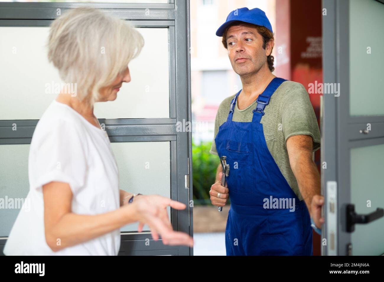 Skilled male plumber talking with woman homeowner Stock Photo - Alamy