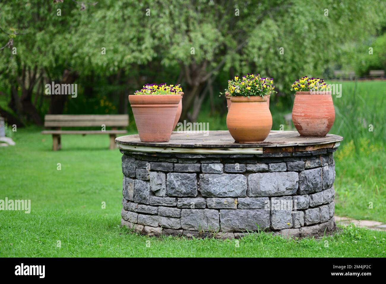 Water well cover decorated with flower pots Stock Photo - Alamy