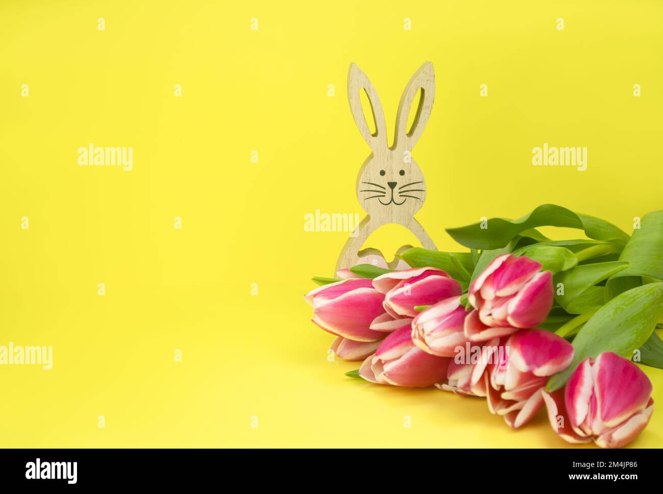 Easter. Wooden rabbit and pink tulips on a yellow background Stock ...