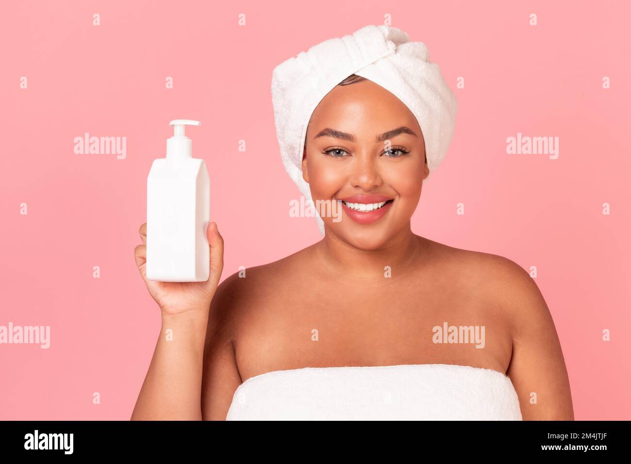 Attractive african american plus size lady with bottle of moisturising ...