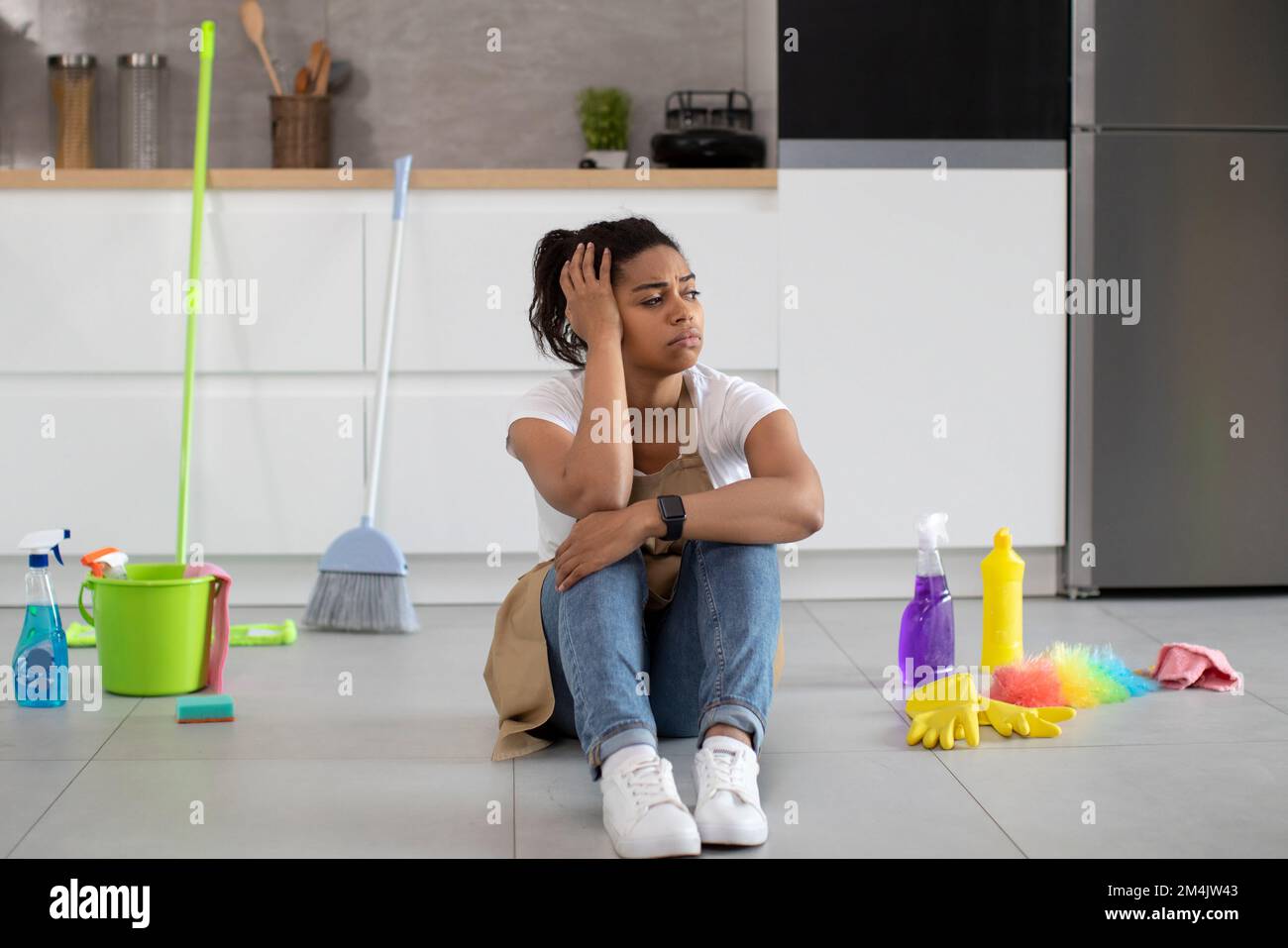 Upset tired millennial african american housewife in apron sits on ...